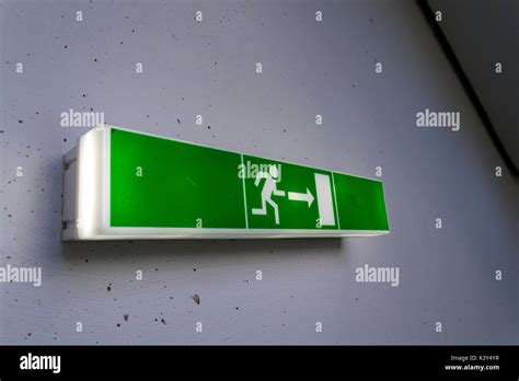 Green Shining Escape Exit Sign On White Concrete Wall Stock Photo Alamy