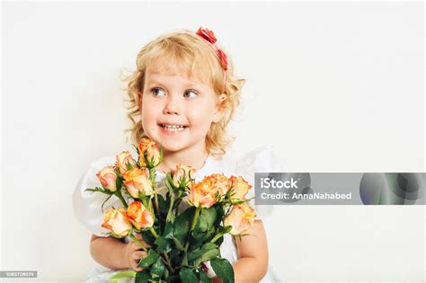 소녀의 귀여운 3 세 유아 입고 흰색 경우 스튜디오 촬영 드레스 노란색 오렌지 장미 꽃다발을 들고 가족에 대한 스톡 사진 및