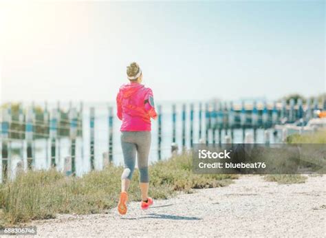건강 한 여성 러너 바다 근처 조깅입니다 휘트니스 여자 운동 분홍색 운동복과 신발에서 실행 되는 액티브 라이프 스타일 훈련 심장
