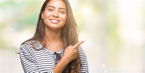 젊은 아름 다운 아랍 여자 손과 카메라 보고 얼굴에 행복 하 고 자연 식 가진 측까지 손가락으로 가리키는 얼굴의 미소와 쾌활 한 고립 된 배경 위에 선글라스를 착용