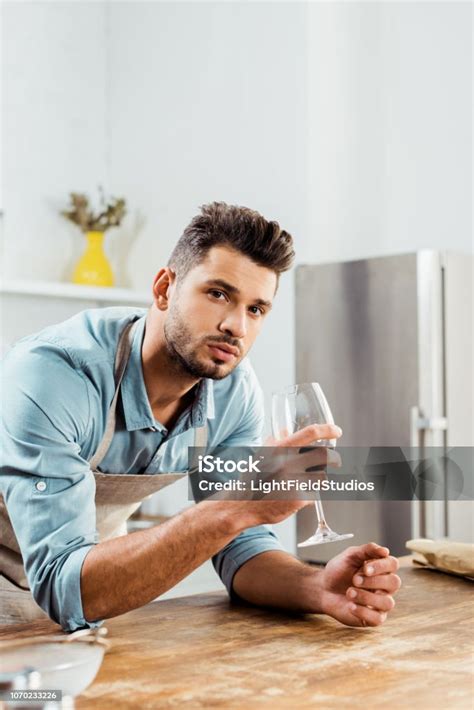 잘생긴 젊은 남자 앞치마 와인 잔을 들고와 주방에서 요리 하는 동안 카메라를 보고 건강한 생활방식에 대한 스톡 사진 및 기타 이미지 건강한 생활방식 건강한 식생활