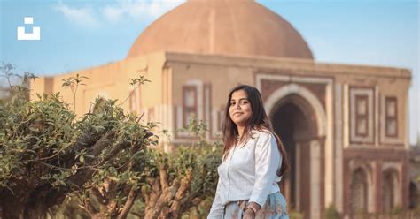 긴 치마를 입은 여자가 건물 앞에 서 있다 사진 Unsplash의 무료 꾸뜹미나르 이미지