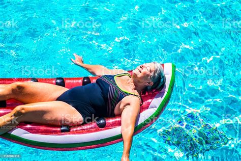 행복 한 아름 다운 노인 수석 레이디 수 박에 신선한 물을 즐기고 수영장의 푸른 물에 풍선 매트리스는 여름 화창한 날에 미소와 휴식 수영장 스포츠 경기장에 대한 스톡 사진