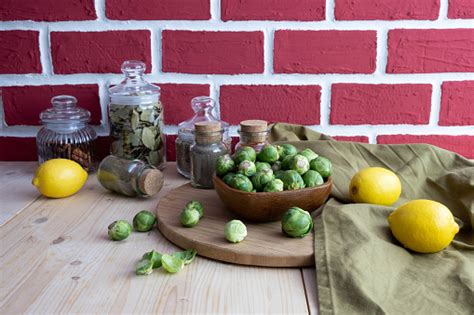 껍질을 벗기지 않은 브뤼셀 콩나물은 테이블에 레몬과 향신료 근처 나무 그릇에 누워 0명에 대한 스톡 사진 및 기타 이미지 0