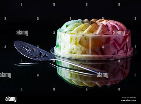 A Rainbow Coloured Jelly Mold Dessert Reflecting On A Glass Table