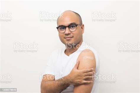 젊은 아시아 남자는 코로나 백신을 받았다 고립 된 흰색 배경에 코로나 바이러스를 예방 접종 을 받은 후 붕대와 어깨를 보여주는 아시아 남자의 초상화 30 34세에 대한 스톡