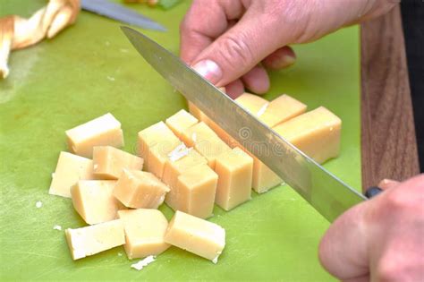 Hands With A Knife Cut The Cheese Into Cubes Close Up Stock Image