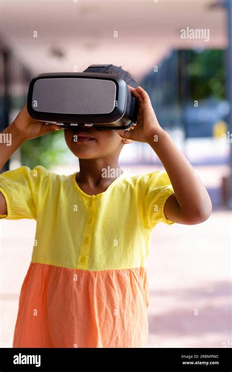 Biracial Schoolgirl Using Vr Headset In Sunny School Corridor With Copy Space Education