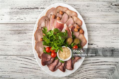 육류와 소시지와 견과류 접시에 슬라이스 마늘 소스 훈제 고기 구운 햄 쵸 릿 죠 베이컨 올리브 체리 토마토 흰색 질감된 나무 테이블의 배경에 대 한 접시에 고기에 대한 스톡