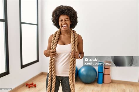 전투 밧줄과 체육관 훈련에서 아프로 머리를 가진 젊은 아프리카 계 미국인 여성은 섹시한 표정 쾌활하고 행복한 얼굴로 카메라를보고 윙크 곱슬 머리에 대한 스톡 사진 및 기타