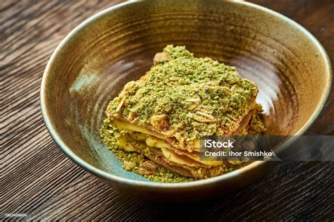 퍼프 페이스트리와 바닐라 슬라이스 또는 커스터드 슬라이스 피스타치오의 Ayers와 프랑스 디저트 밀feuille의 군침이 도는 조각 나무 배경에 접시에 제공 나폴레옹 케이크