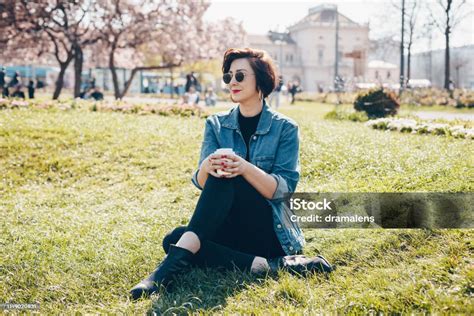 공원에 앉아 휴식을 취하는 아름 다운 여자 가 서 커피를 마시는 매력적인 갈색 머리의 초상화 따뜻한 봄 날 야외에서 즐기는 현대