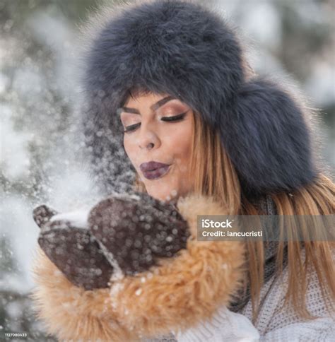 갈색 모피 모자와 재킷은 겨울을 즐기는 매력적인 여자 세련 된 금발 소녀 눈 덮여 다리에 대 한 포즈의 측면 보기 옷이 추운 날씨와 아름 다운 젊은 여성 갈색에 대한 스톡