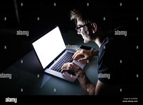 Young Concentrated Man Using Laptop Computer At Home Indoors At Night Looking At Laptop White