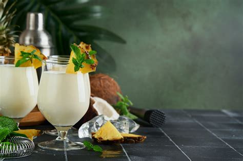피나콜라다 럼 파인애플 주스 코코넛 크림으로 만든 전통적인 카리브해 칵테일과 열대 과일 신선한 녹색 배경에 바 도구가 있습니다 여름 열대 칵테일과 휴식 개념 피나 콜라다에