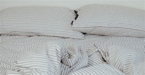 줄무늬 이불과 베개가 있는 정돈되지 않은 침대 사진 Unsplash의 침대 이미지