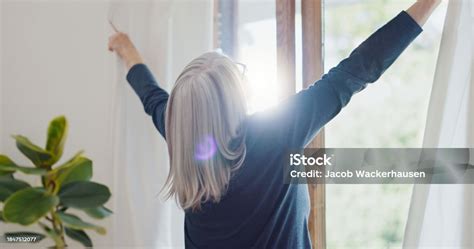 집에 있는 노인 여성이 커튼을 열고 태양 빛 신선한 공기로 하루를 준비합니다 아침의 일과 은퇴나 고령자가 아파트 창가에서