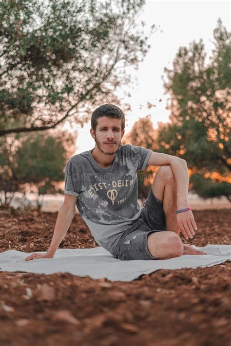 Young Arab Model Sitting On A White Picnic Blanket Outdoors Stock Image