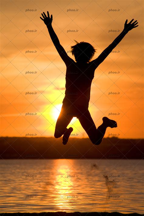 عکس مرد شاد در حال پریدن در کنار دریاچه عکس با کیفیت و تصاویر استوک