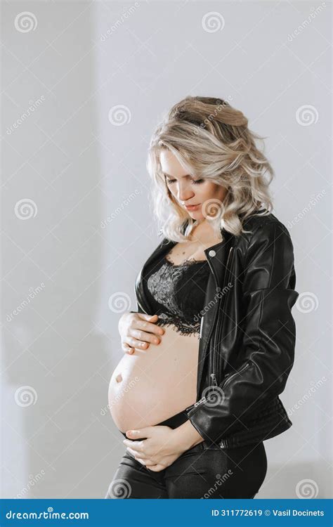 Stylish Studio Portrait Of A Beautiful Pregnant Young Woman In A Black