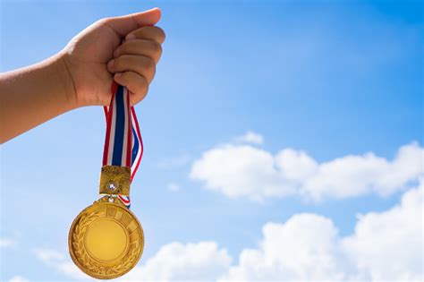 승자가 손을 푸른 하늘에 대 한 타이 리본 골드 메달을 들고 발생 합니다 골든 메달 수상 스포츠 또는 비즈니스에 대 한 높은