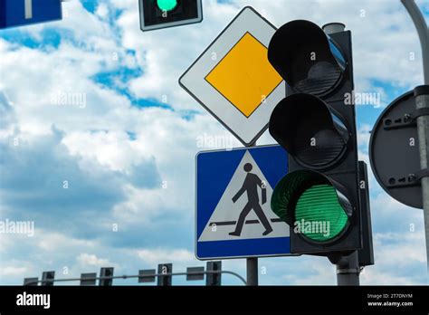 green light at traffic light with sign pedestrian crossing and road