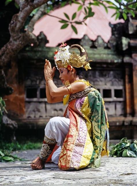 A Woman Sitting On The Ground With Her Hands Clasped To Her Face And Wearing A Headdress