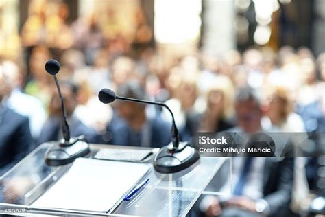마이크에 초점이 맞춰져 있고 비즈니스 컨퍼런스 기업 프레젠테이션 워크샵 코칭 교육 기자 회견 회사 회의 공개 또는 정치 행사에서 배경에 있는 알아볼 수 없는 사람들 교습에