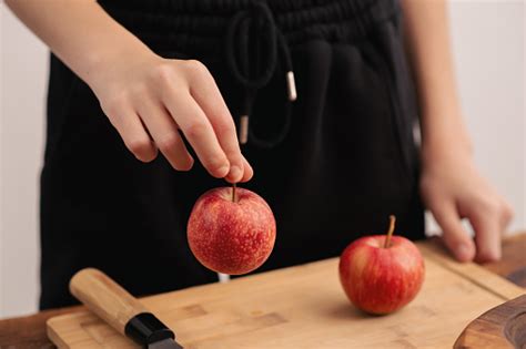 나무 배경에 놓인 여성의 손과 싱싱한 빨간 사과는 건강한 선택 채식주의 식사에 과일을 포함하는 영양학적 혜택이 주는 요리의