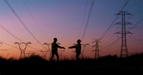 전력선 악수 전기 회로 및 전압 인프라를 위한 해질녘의 사업가 엔지니어링 팀워크 전선 그리드 케이블로 악수하는 기술자의 실루엣
