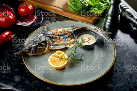 흰색 소스와 붉은 캐비어가 있는 오븐에서 구운 스테렛은 어두운 대리석 배경의 회색 접시에 담겨 있습니다 레스토랑 음식 해산물 0