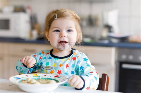 可爱的女婴从勺子蔬菜面条汤吃食物儿童喂养和发展理念可爱的蹒跚学步的女儿高清图片下载 正版图片502698429 摄图网