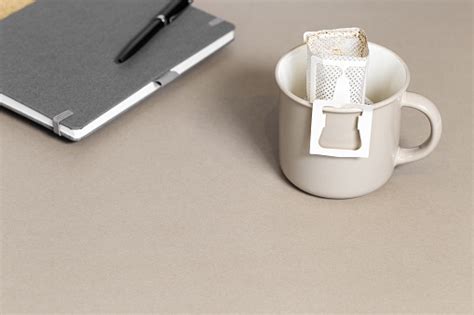 사무실 테이블에 큰 컵에 분쇄 커피와 드립 커피 가방 베이지 색 배경에 양조를위한 종이 가방 드립 커피 필터 패키지 복사 공간이