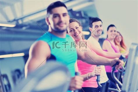 一群年轻人在现代体育馆的跑步机上跑步。高清摄影大图 千库网