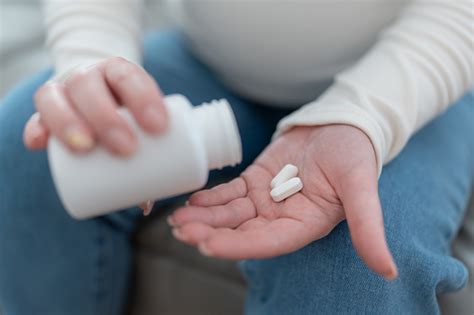 알 수 없는 임산부 알약이 든 항아리를 들고 있는 여성 비타민을 복용하는 모습 임신 중 질병을 치료하는 모습 집에서 소파에 앉아 있는 모습 닫기 가정 생활에 대한 스톡 사진