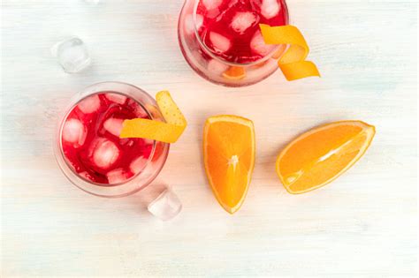 화이트 나무 배경의 상단에서 텍스트를 위한 장소로 촬영 한 얼음 조각과 오렌지 조각이 있는 캄 파리와 오렌지 트위스트 다루어와