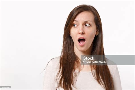 밝은 옷을 옆으로 보고 스튜디오에서 흰색 벽 배경에 고립 된 입을 넓게 열어 주는 충격 젊은 여자의 초상화 사람들은 진심으로 감정 라이프 스타일 개념입니다 복사 공간을 모의