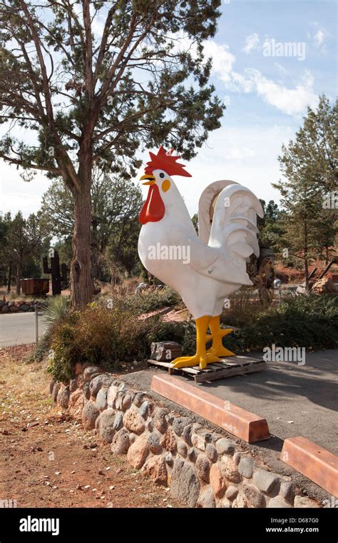 A Rooster Figure Next To A Road And The Red Rocks In The Backdrop