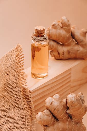베이지 색 배경에 에센셜 생강 오일 생강 뿌리의 유리 병 건강한 대안 생활 스킨케어 바디 케어 헤어케어 크리에이티브 컴포지션을 위한 천연 화장품 성분 Adaptogen에