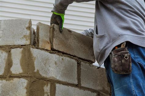 Premium Photo Worker Installing Cement Block Building A Wall For A House