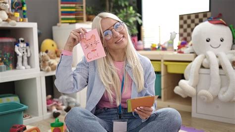 Young Blonde Woman Preschool Teacher Having Vocabulary Lesson At