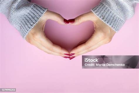 여성의 손은 심장 기호를 만들기 아름다운 광택 매니큐어와 회색 니트 스웨터 직물에 여자의 손 부르고뉴 복사 공간 핑크 배경에 어두운 빨간색 색상 손톱 손톱에 대한 스톡 사진