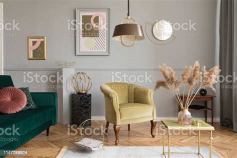 우아한 녹색 벨벳 안락의 자 및 소파 커피 테이블 대리석 스탠드 디자인 램프 및 세련 된 액세서리와 아파트 인테리어의 세련 되 고 고급 스러운 거실 회색 벽에 추상