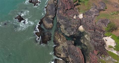 A Columnar Basaltic Or Rock Formation With Breaking Waves On Beach