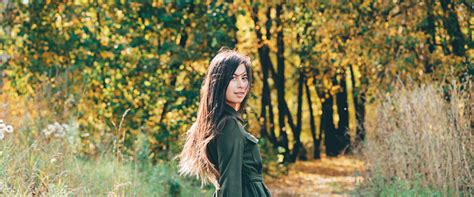 화려한 나뭇잎을 배경으로 햇빛을 받는 길고 자연스러운 검은 머리를 가진 꿈꾸는 소녀 가을 숲에 있는 낙엽과 아름다운 소녀 화창한 날에 생생한 단풍 사이에 있는 여성의