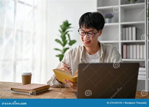 Portrait Of Young Asian Man Writing On Notebook While Working With Laptop Stock Image Image Of