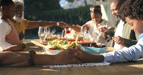 손을 잡고 흑인 가족과 축하 부활절 또는 함께 식사를 위해 파티오에서 점심을 먹습니다 조부모 부모 자녀 믿음 감사 감사의 마음으로 가정에서 음식과 음료와 사랑을 베풀어