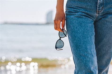 부드러운 바다 푸른 하늘 배경 콘텐츠 여름 휴가 및 여행 개념에 대 한 복사 공간에 대 한 해변에 걷는 검은 색 선글라스와 아름 다운 그을린 여자 손의 자른 샷 보기