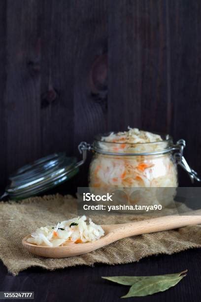 검은 색 배경에 유리 항아리와 나무 숟가락에 허브와 당근과 수제 소금에 절인 양배추 나무 테이블에 자루가 있는 양배추절임 복사 공간을 복사합니다 수직 채식 음식 건강한