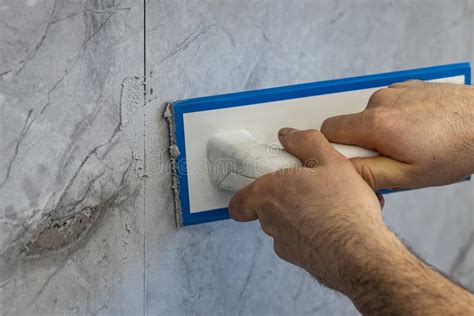 Professional Worker Applying Grout On Ceramic Tile Wall With A Rubber